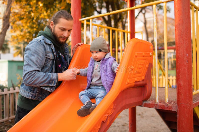 Dad and Child are Playing on the Playground. Swing and Slide Rides ...