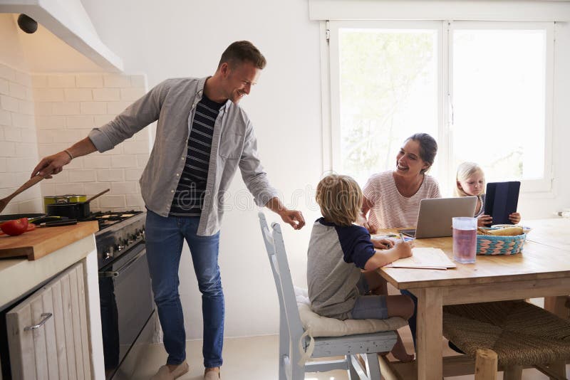 Dad Cooking Turns To Mum with Kids at the Kitchen Table Stock Photo ...