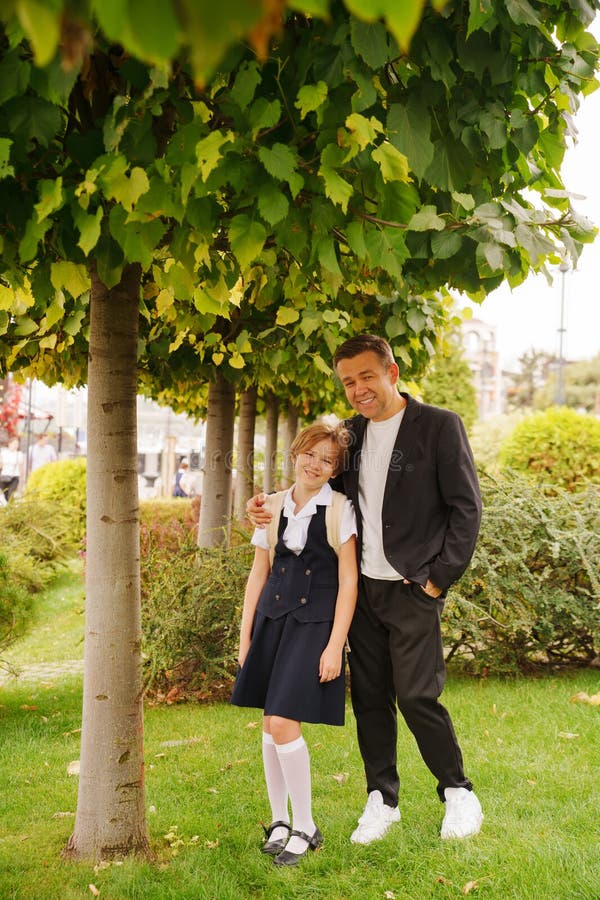 Dad and Daughter in School Uniform on the Lawn Under a Tree. Stock ...