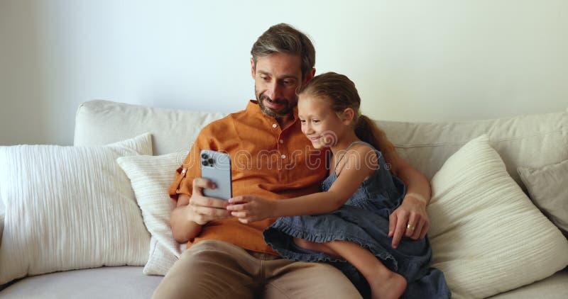 Dad and Daughter Sit on Sofa Using Mobile Phone Stock Footage - Video ...