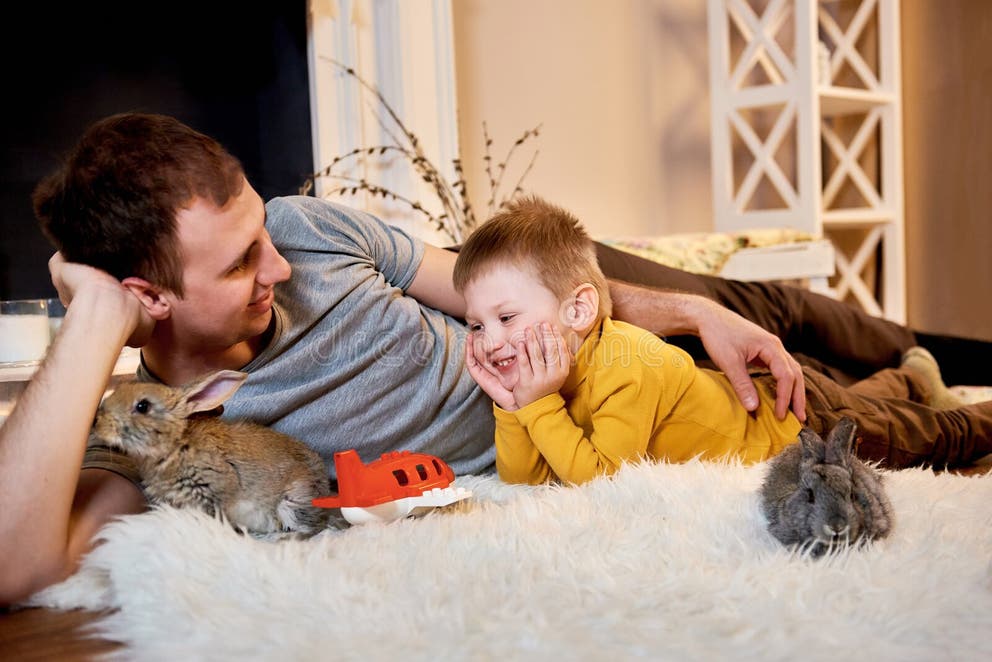 Dad and Son are Playing with the Rabbits at Home. Stock Image - Image ...