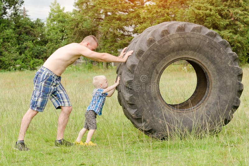 Dad and Son Push a Big Tire. Street Workout Stock Photo - Image of ...