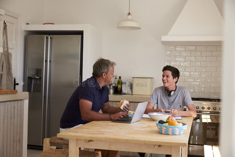 Dad and Son Using Technology Eat and Talk at Kitchen Table Stock Image ...