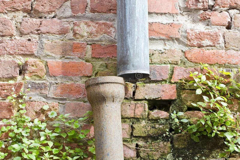 Damaged Old Rusty Copper and Cast Iron Downpipe Against a Brick Wall ...