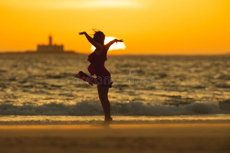 Dancer Performing on the Beach at Sunset with Lighthouse in Background ...