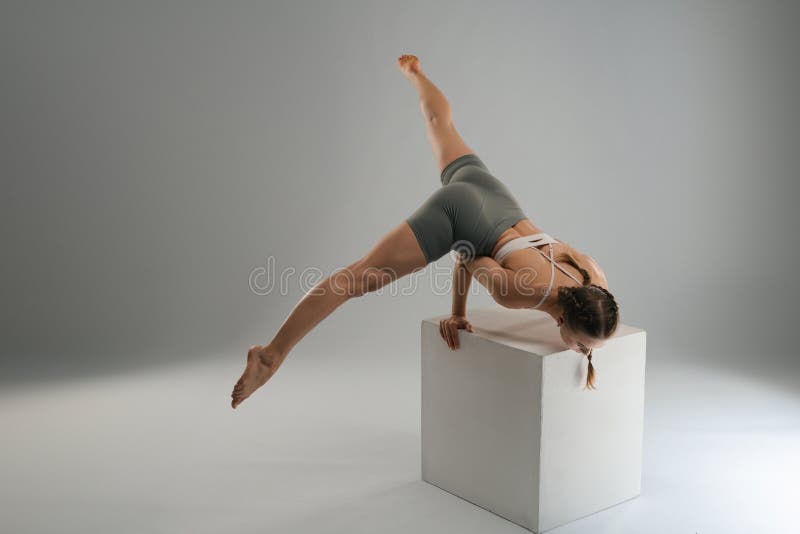 Dancer Performing an Elegant Pose on a White Cube in a Studio Setting ...
