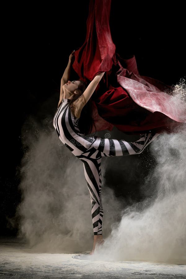 Dancer Performs Dynamic Movement with Red Fabric in a Dramatic Setting ...