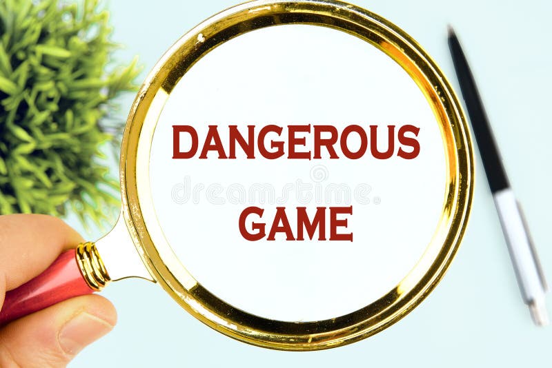 DANGEROUS GAME Words through a Magnifying Glass in His Hand on a White ...