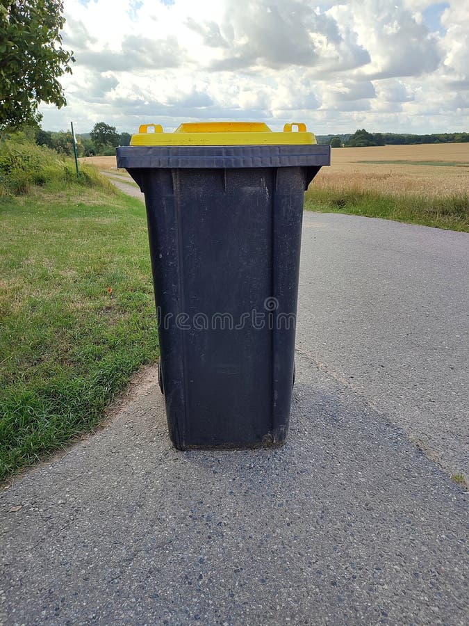 A Dark Garbage Can with a Yellow Lid for Plastic Waste Stands Alone on ...