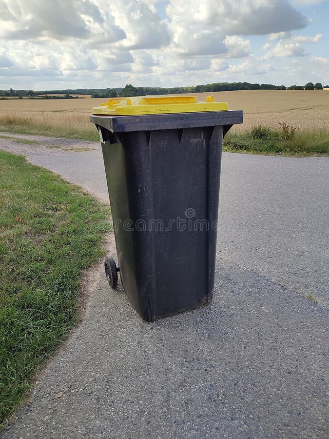 A Dark Garbage Can with a Yellow Lid for Plastic Waste Stands Alone on ...