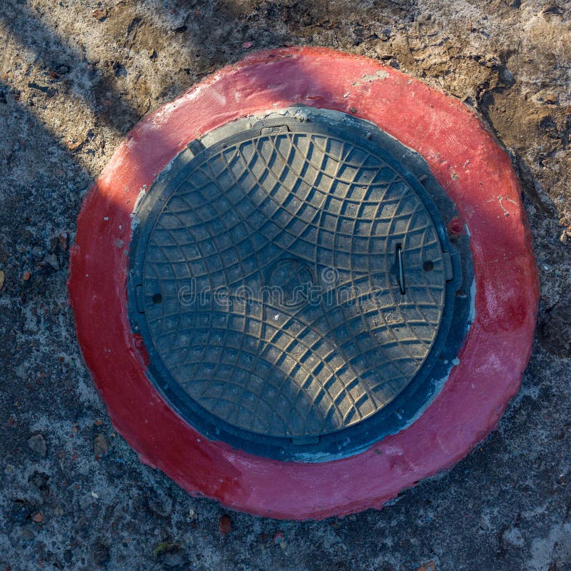 A Dark Gray Manhole Cover Set within a Reddish-brown Circular Frame ...