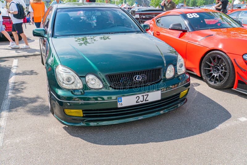 A Dark Green, Modified Sedan is Parked on an Asphalt Surface with Side ...
