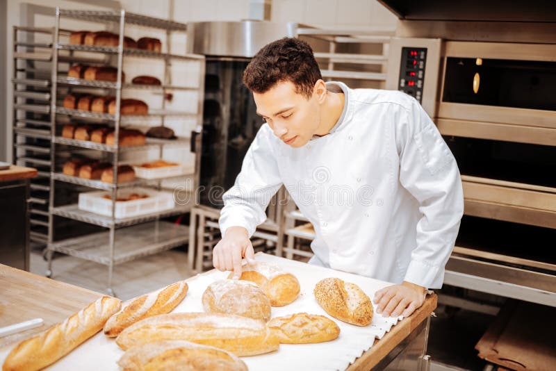 Dark-haired Baker Touching the Loaf of Bread after Baking the Tray ...