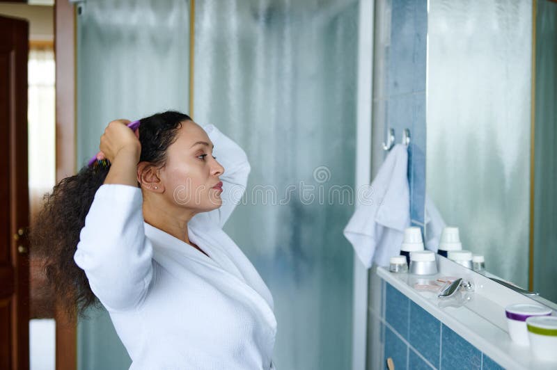 Dark Haired Mature Woman In A White Waffle Bathrobe Combing Hair