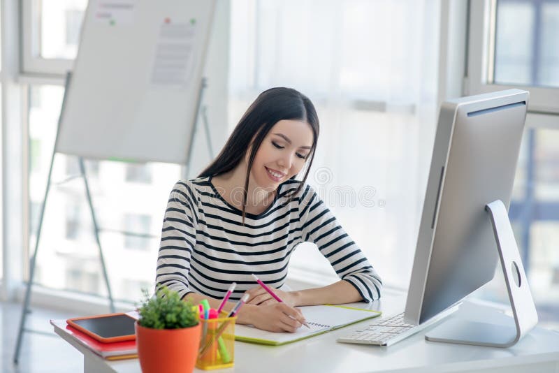 Dark-haired Pretty Woman in a Striped Shirt Making Notes Stock Photo ...