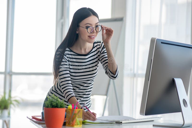 Dark Haired Woman In A Striped Shirt Looking At The Computers Screen