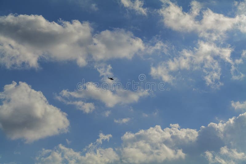 A Dark Helicopter Flying Overhead with a Cloudy Blue Sky in the ...