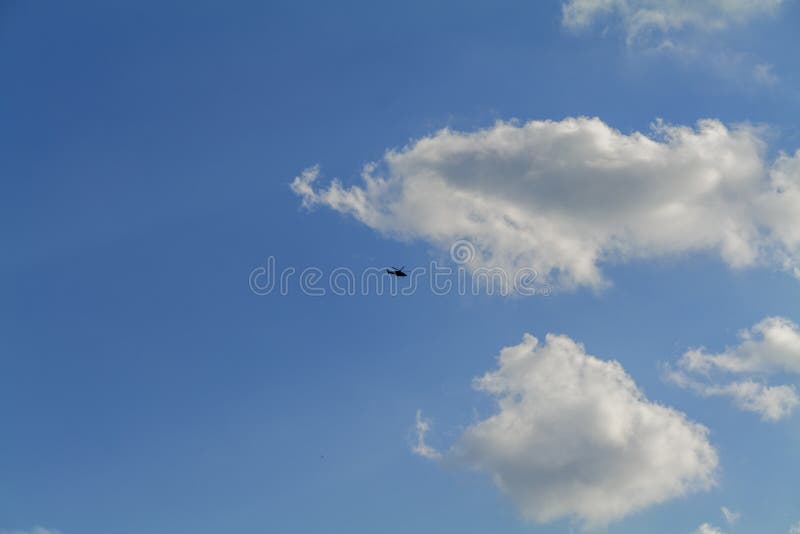 A Dark Helicopter Flying Overhead with a Cloudy Blue Sky in the ...
