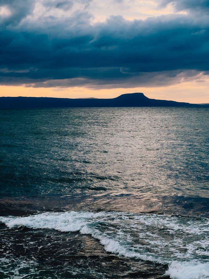 Dark and Moody Seascape Capturing Rolling Waves As Sun Sets Behind ...