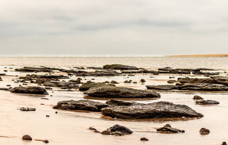 Dark rocks on the beach stock photo. Image of rocks - 213061044
