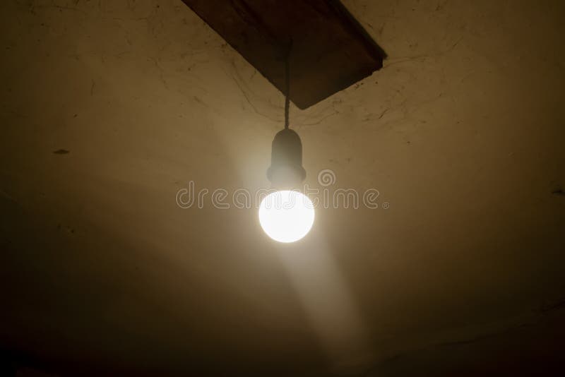In a Dark Room, a Light Bulb Glows Under the Ceiling. the Gloomy ...
