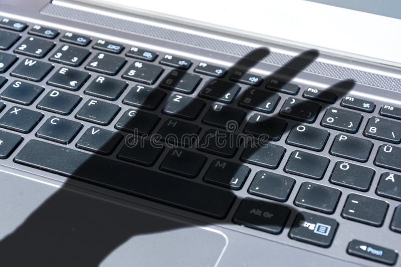 Dark Shadow of a Hand Reaches for Computer Keyboard Symbolizing Cyber ...