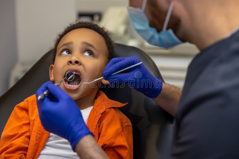 Dark-skinned Boy Looking Scared while Doctor Checking Up His Teeth ...