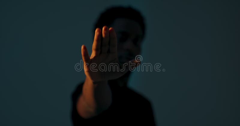 Dark Skinned Man in a Dark Studio with Light Stretches His Hand Forward ...