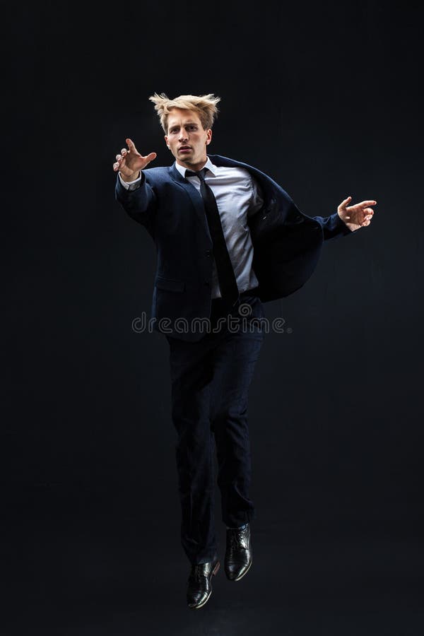 In a Dark Studio, a Man in a Sharp Navy Suit Leaps Mid-air, Stock Image ...