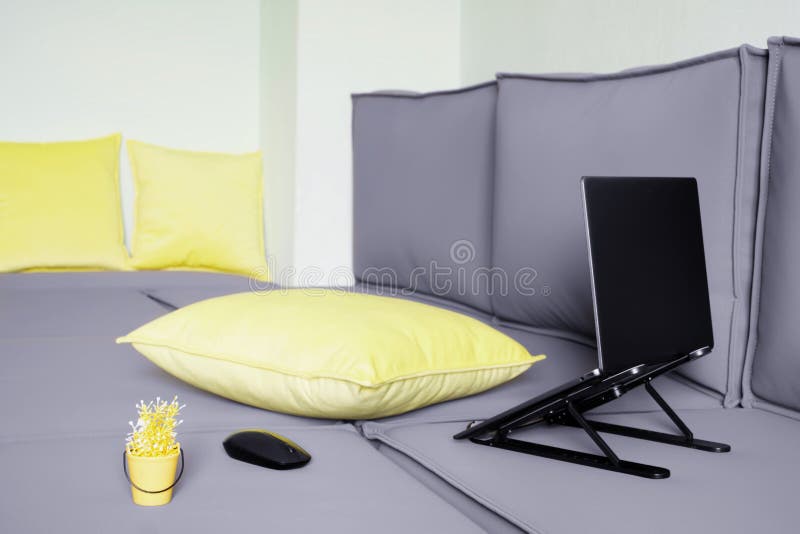 Dark Thin Laptop on a Stand, a Computer Mouse and Cozy Yellow Pillows ...
