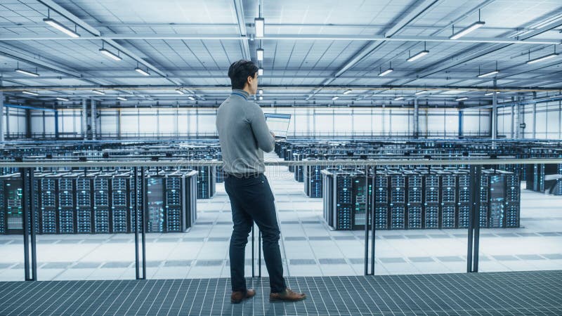 Data Center Engineer Using Laptop Computer. Server Farm Cloud Computing Specialist Facility with ...