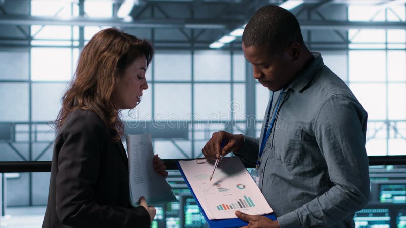 Data Center Team Examines Paperwork Files in Server Room, Reviewing ...