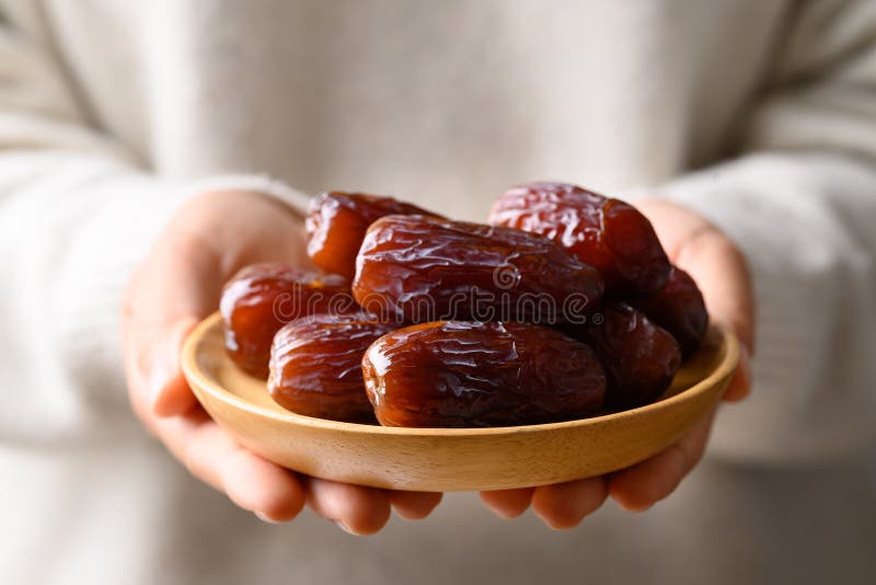 Date Palm Fruit (MedJool) on Wooden Plate Holding by Hand Stock Image ...