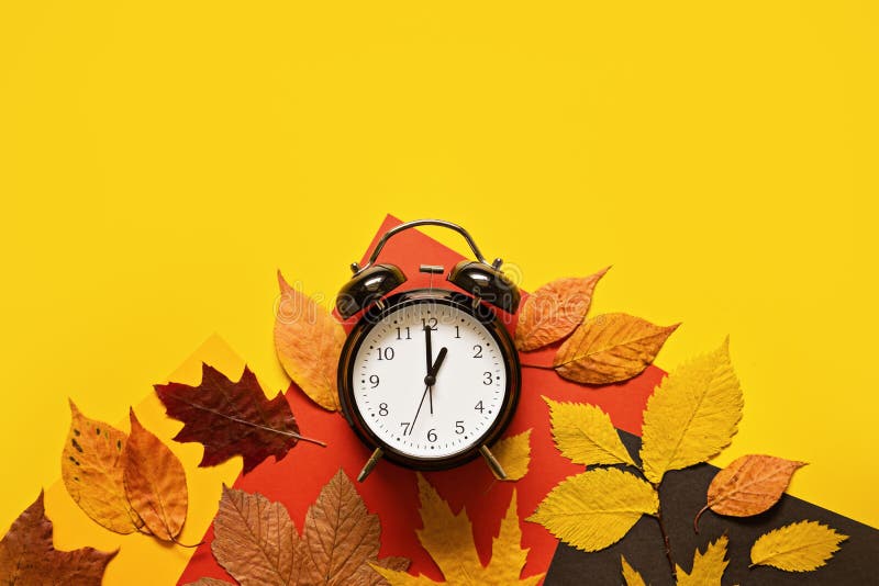 Daylight Saving Day. Fall Back. Black Alarm Clock and Autumn Leaves on ...
