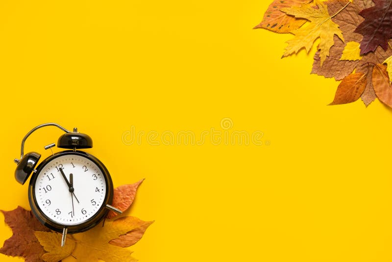 Daylight Saving Day. Fall Back. Black Alarm Clock and Autumn Leaves on ...