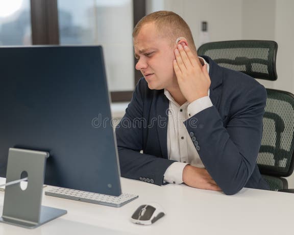 A Deaf Man Works at a Computer in the Office. Broken Hearing Aid ...