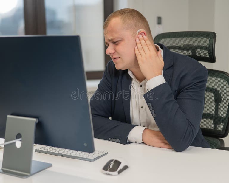 A Deaf Man Works at a Computer in the Office. Broken Hearing Aid ...