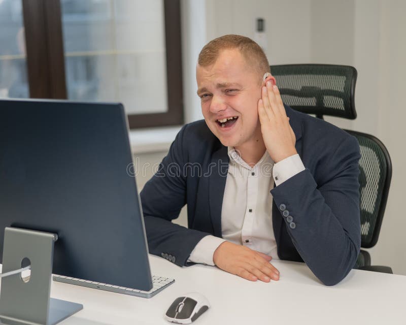 A Deaf Man Works at a Computer in the Office. Broken Hearing Aid ...