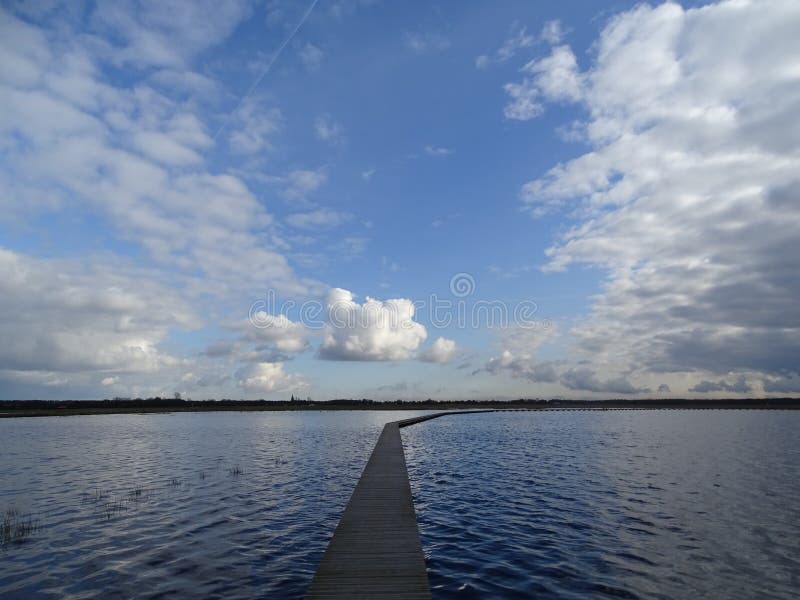 A Decking Path through the Water, with a Blue Sky with White Clouds ...