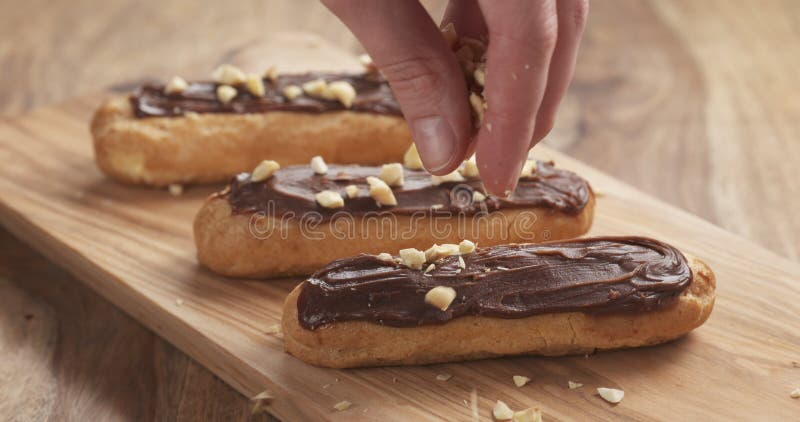 Decorating Eclairs with Hazelnuts on Wood Board Stock Image - Image of ...