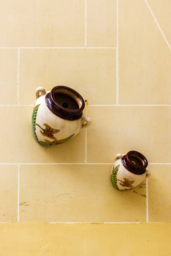 Two Decorated Ceramic Pots Mounted on a Textured Beige Wall Surface ...