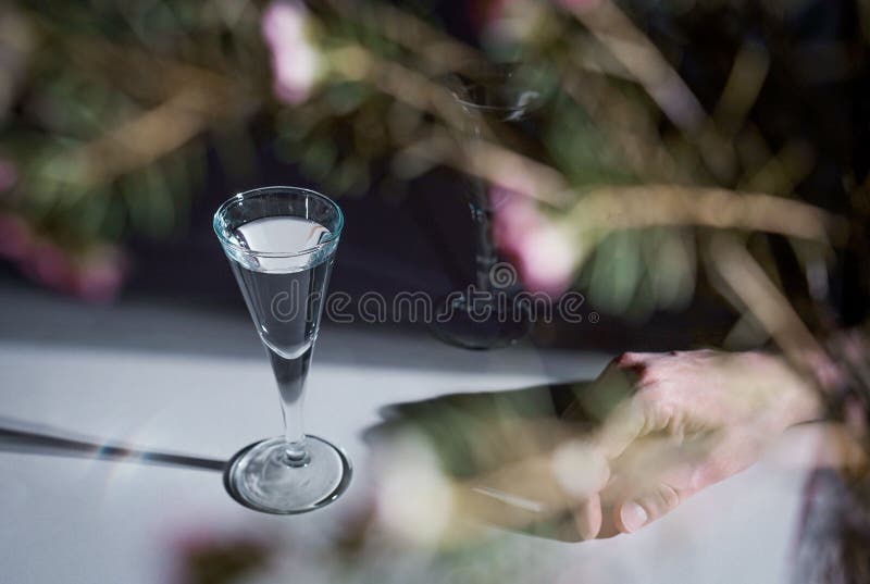 Decorative Elegant Glass with a Clear Liquid on a Table with a Hand ...