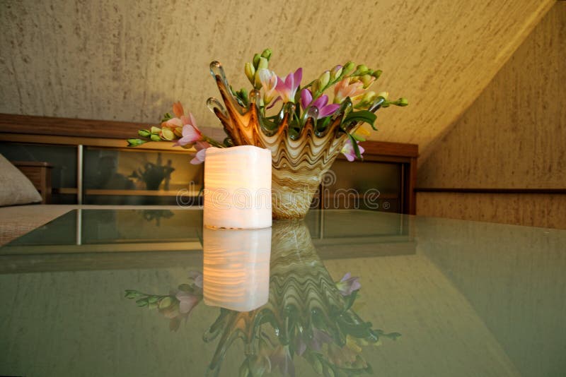 Decorative Flowers and a Candle on a Glass Table. Reflection on the ...