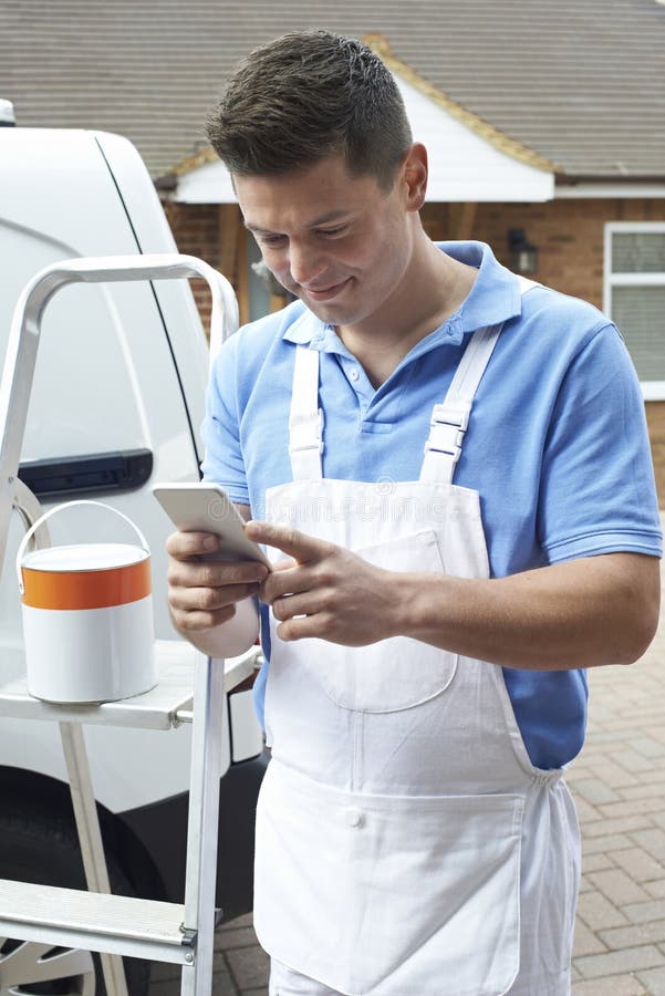 Decorator Using Mobile Phone Standing Outside Domestic Home Stock Photo ...