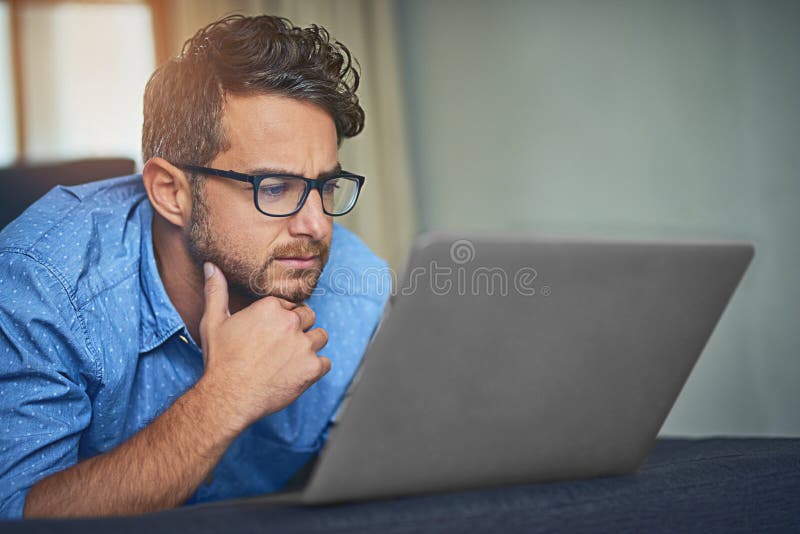Deep in the Browser. a Young Man Using a Laptop on the Sofa at Home ...