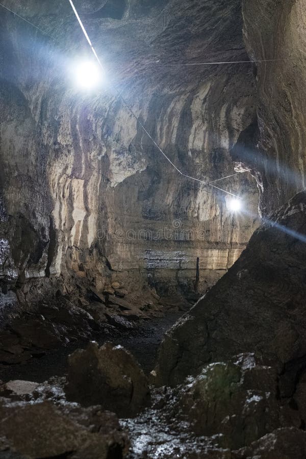 Deep, Illuminated Natural Cave with Rough Rock Formations and a Dimly ...