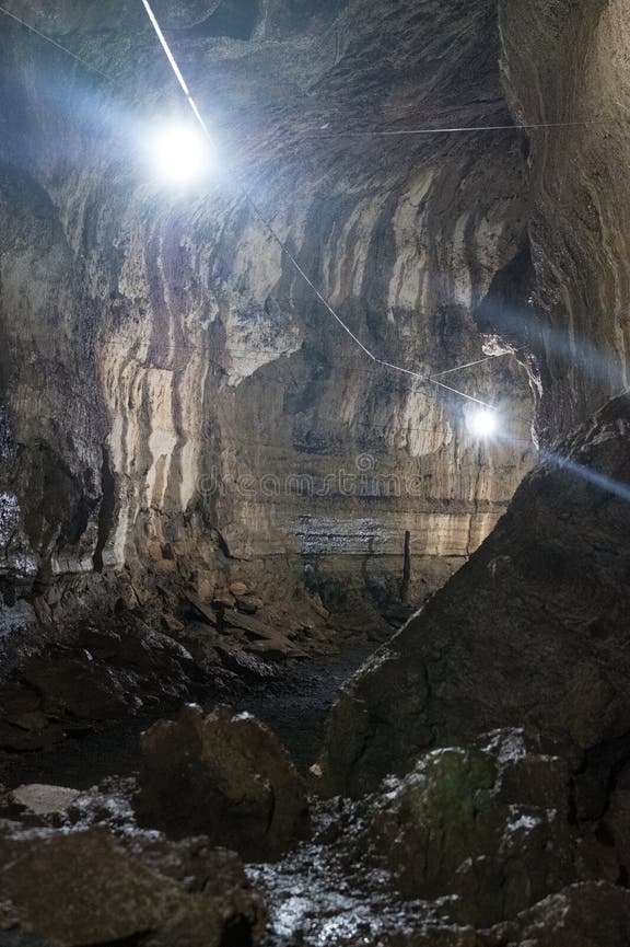 Deep, Illuminated Natural Cave with Rough Rock Formations and a Dimly ...