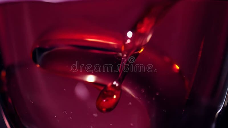 A Deep Red Liquid is Elegantly Swirling in a Glass, Creating ...