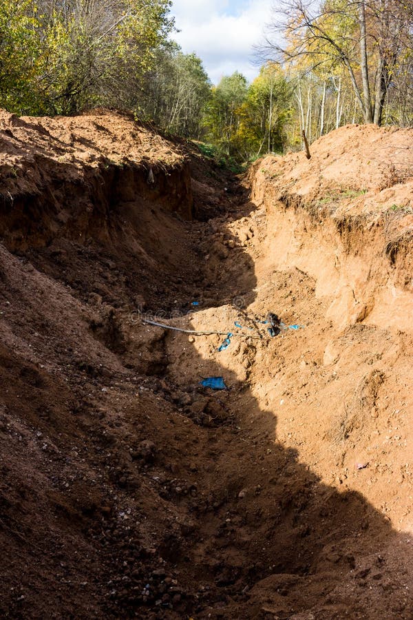 A Deep Trench Dug in Sandy Soil in a Forest Area for Laying Engineering ...