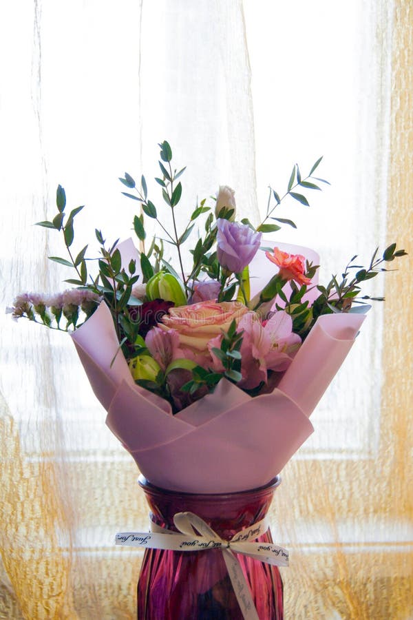 A Delicate Bouquet of Different Flowers in a Light Pink Wrapper Stands ...